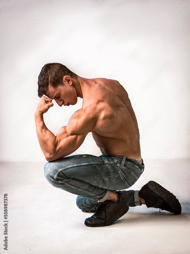 Young bodybuilder in kneeling pose in studio shot Stock Photo | Adobe Stock