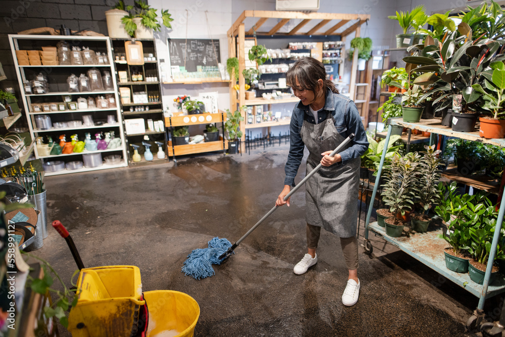 Female worker mopping floor with mop in garden shop Stock Photo | Adobe ...