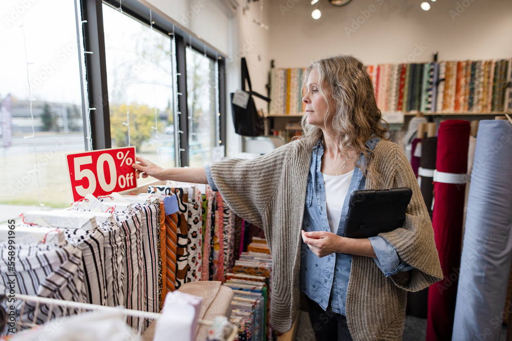Business owner placing sales sign in fabric store window Stock Photo ...