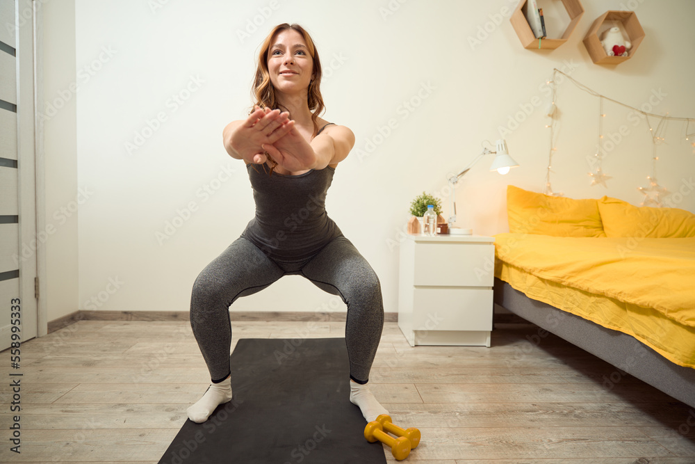 Joyous fit female performing lower-body exercise at home Stock Photo ...