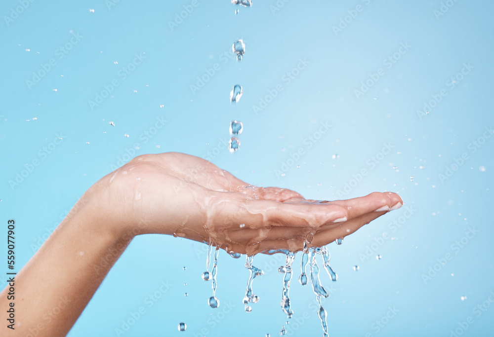 Hand, water and hydration with a woman cleaning in studio on a blue ...