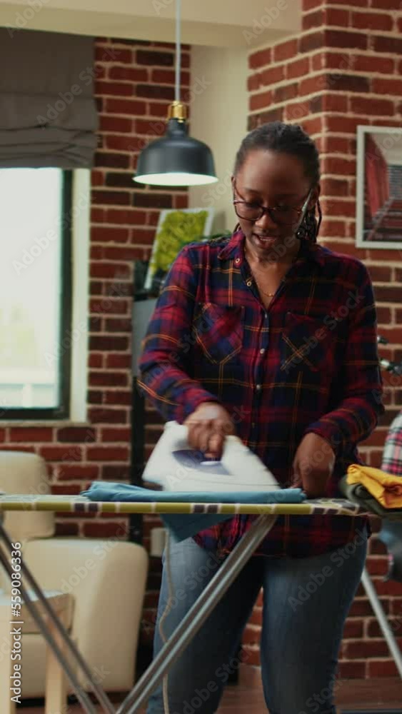 Vertical video: Female adult enjoying doing laundry work at home ...