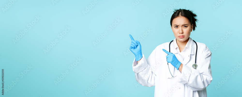 Angry female doctor or nurse, pointing fingers at upper left corner ...