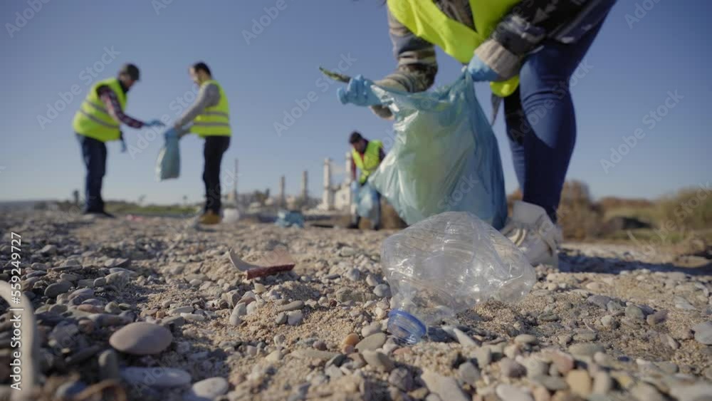 Group of cleanup volunteers cleaning up waste in nature and holding a ...