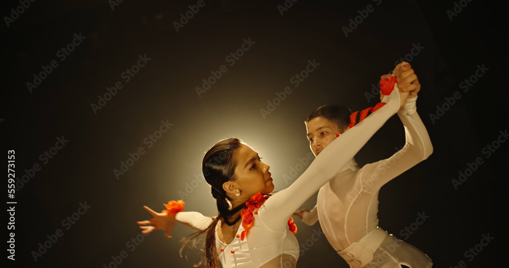 Teen asian kids performing ballroom sport dance on stage with smoked ...