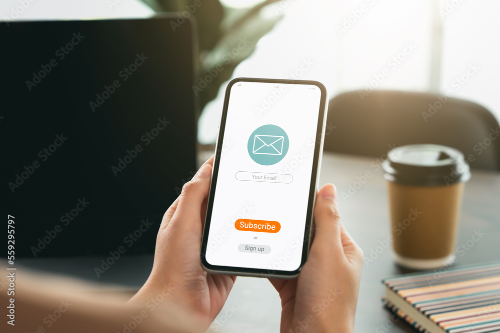 Hand holding smartphone and shows a digital screen of subscribe email ...