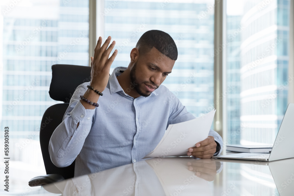 Frustrated African man read bad news in postal letter or paper document ...