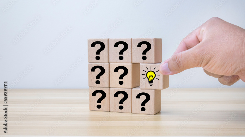 Question mark and creativity concept. Hand holding a wooden cube with a ...