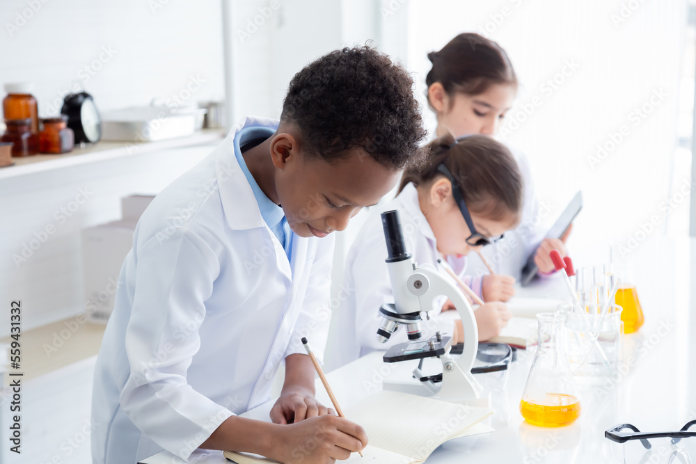 Elementary pupils in white gowns studying a chemical experiment in ...