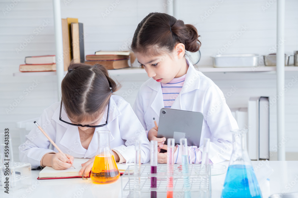 Elementary pupils in white gowns studying a chemical experiment in ...