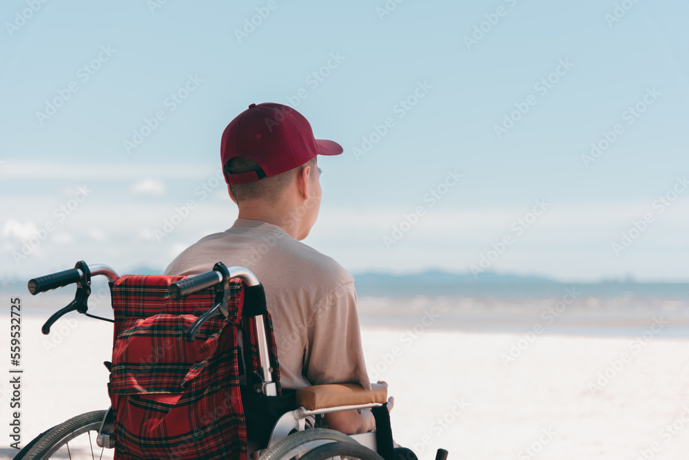 Back of young man with disability wearing a red cap on wheelchair ...
