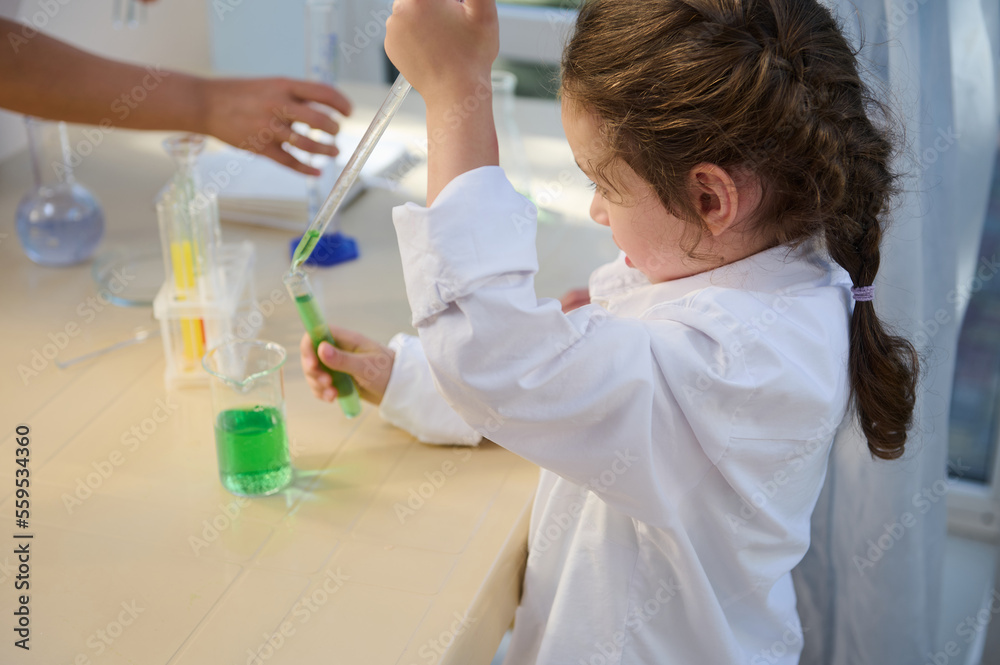 Fotka „Side view of a Caucasian smart kid girl in white lab coat, using ...