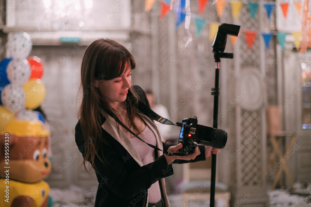Girl photographer with a camera at work on the set in the banquet hall ...