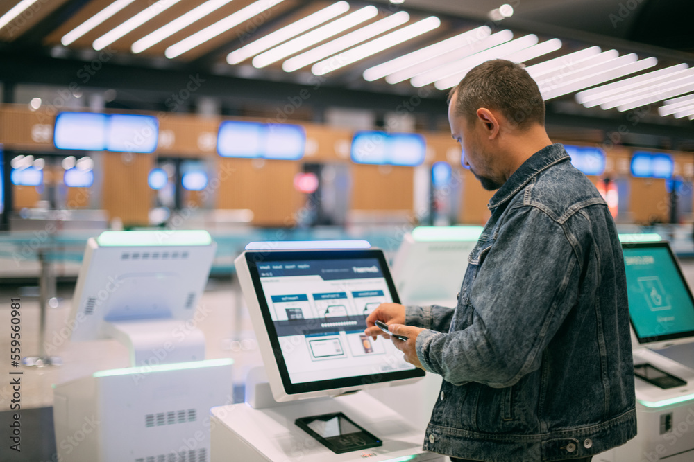 A male passenger at the electronic check-in desk in the departure area ...