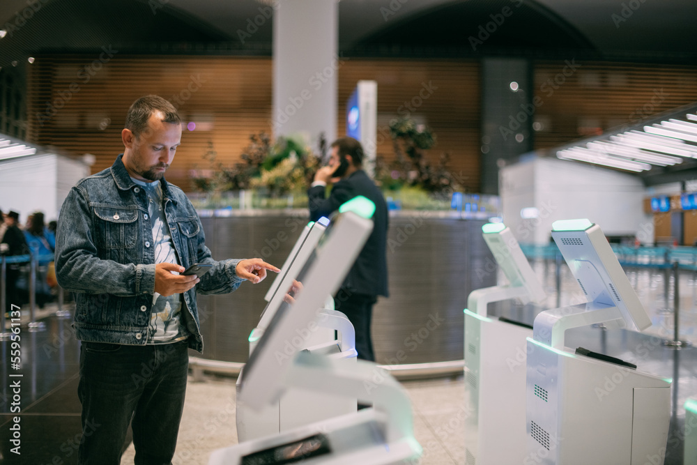 A male passenger at the electronic check-in desk in the departure area ...