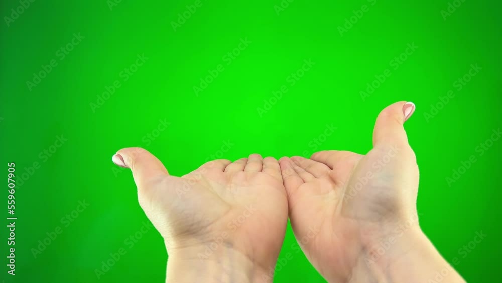 woman stretches her two palms on a green chroma key background where ...