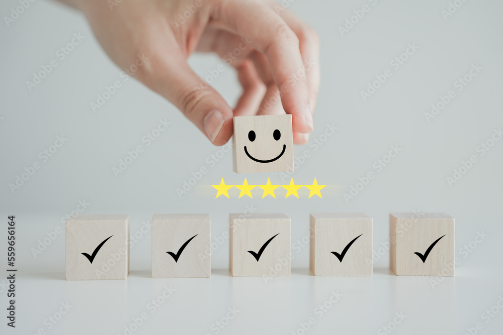 Hand holding smile happy face with 5 star and check mark on wooden ...