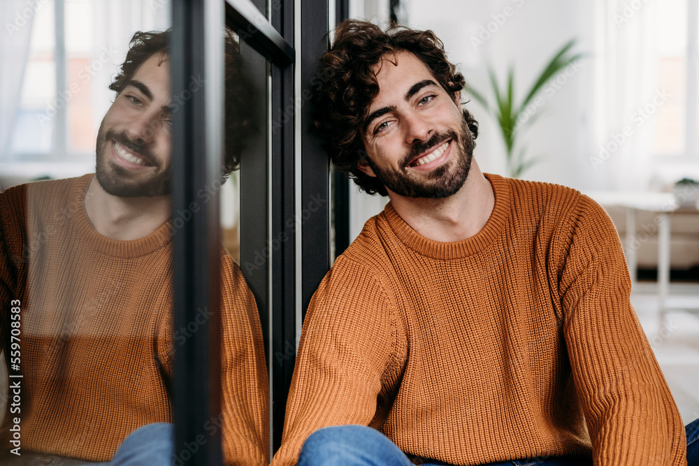 Happy young man leaning on glass door at home Stock Photo | Adobe Stock