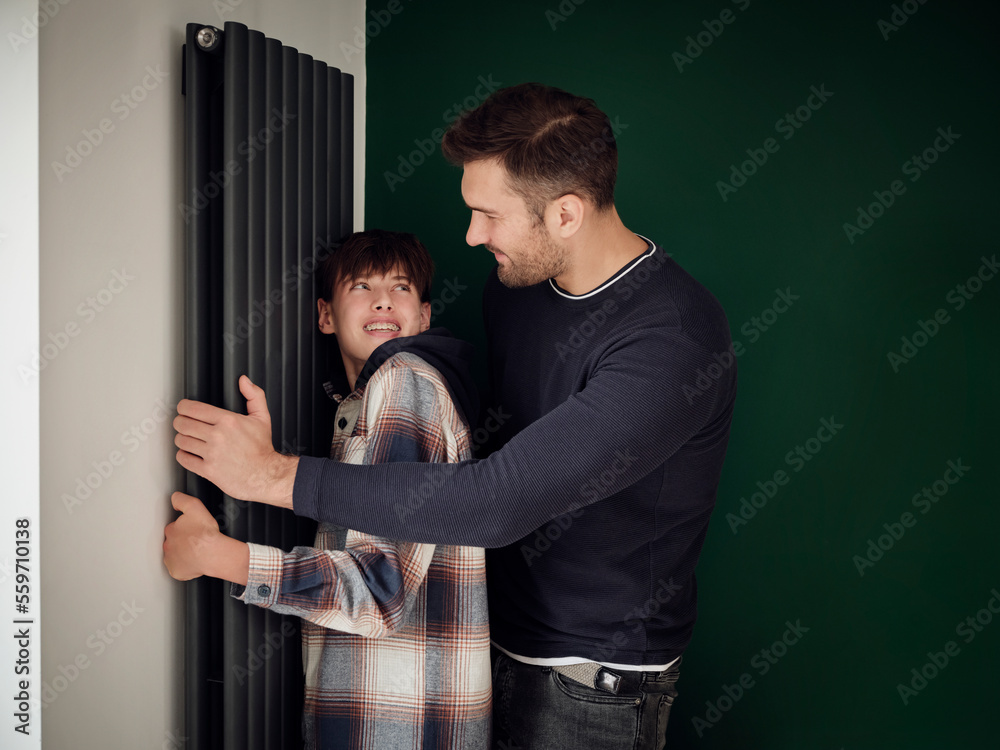Son and father at home touching and hugging radiator Stock Photo ...