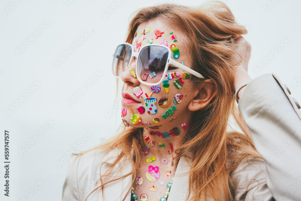 Woman with stickers on face standing eyes closed in front of white ...