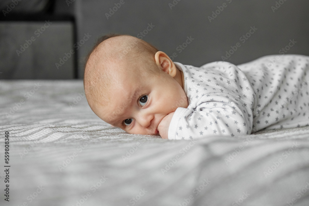 Child care concept. Portrait of cute little baby in bodysuit lying on ...