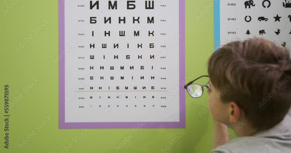 Schoolboy with glasses reads table to check visual acuity. Preventive ...
