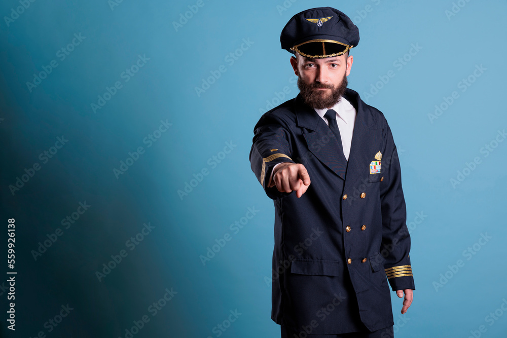 Serious aircraft pilot pointing at camera, plane aviator wearing ...