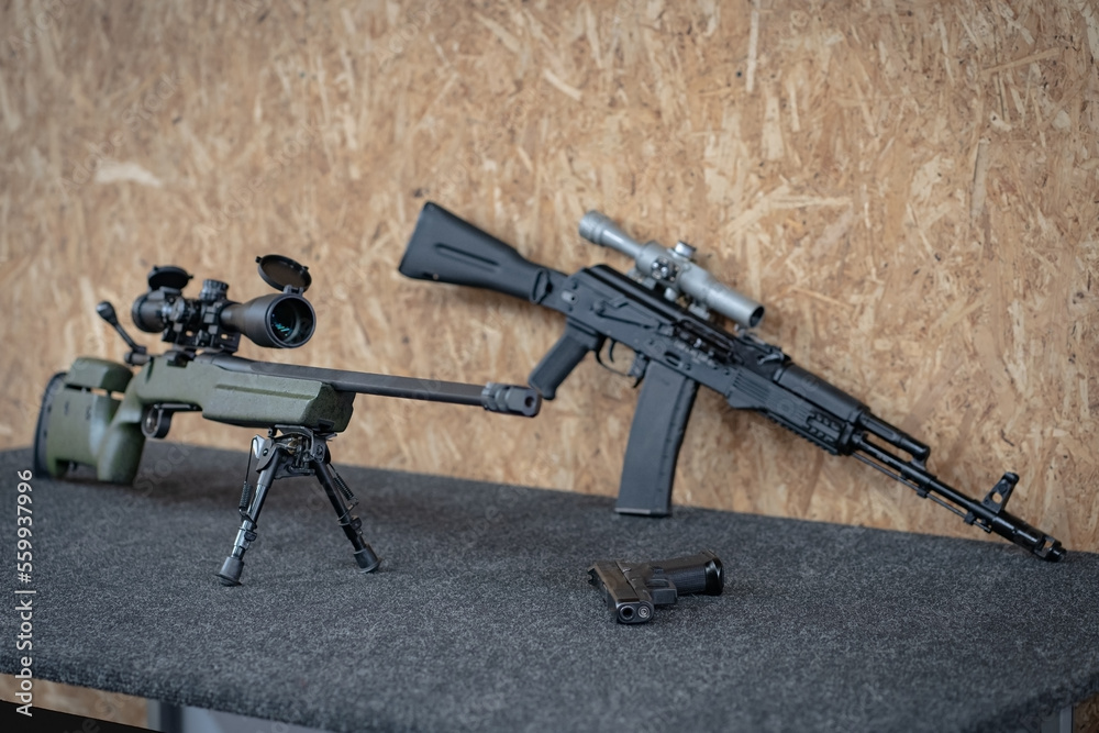 Different firearms in shooting range, sniper rifle, pistol and assault ...