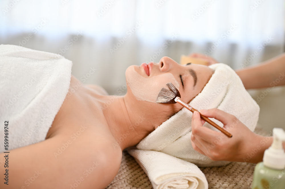 Beautiful Asian woman lying on massage table, receiving facial ...