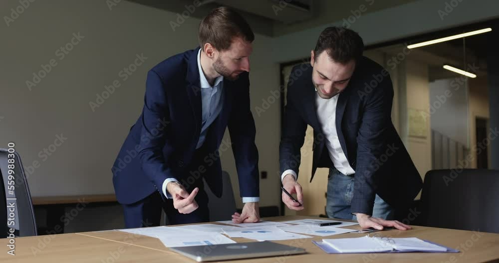 Two businessmen reviewing statistics sales data shown in charts, share ...
