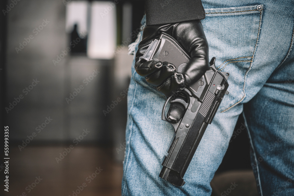 robber in a black glove holds a gun in his hand. for your self defense ...