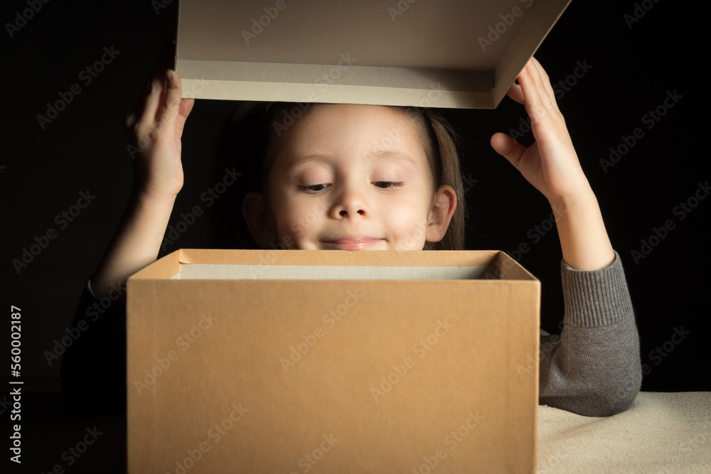Emotional happy smiling little girl opens a long-awaited package with a ...