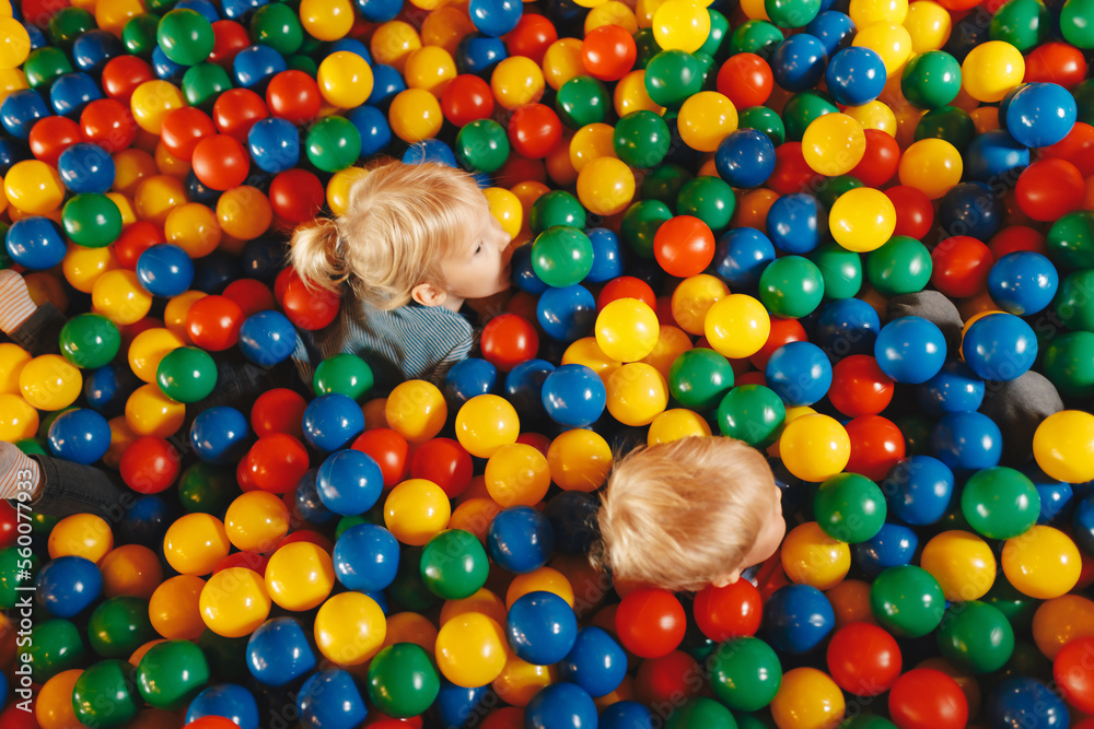 Happy kids playing in amusement park balls pool. Kids cheering and ...