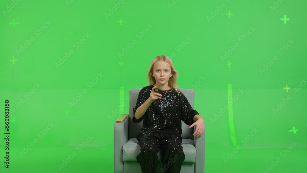 Young girl sitting in front of TV screen in an armchair with a remote ...