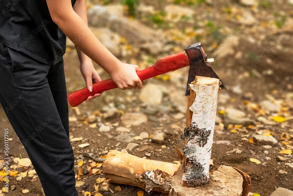 Female strong hands chop firewood with axe for bonfire. Powerful ax ...
