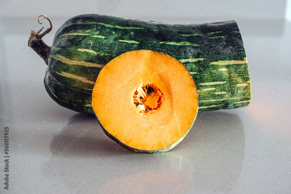 Una rodaja de calabaza apoyada sobre una calabaza larga verde también ...