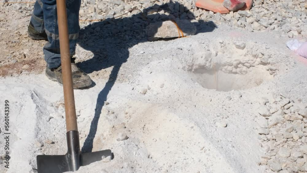 Holes drilled for quarry blast. Placing explosives in holes. The worker ...