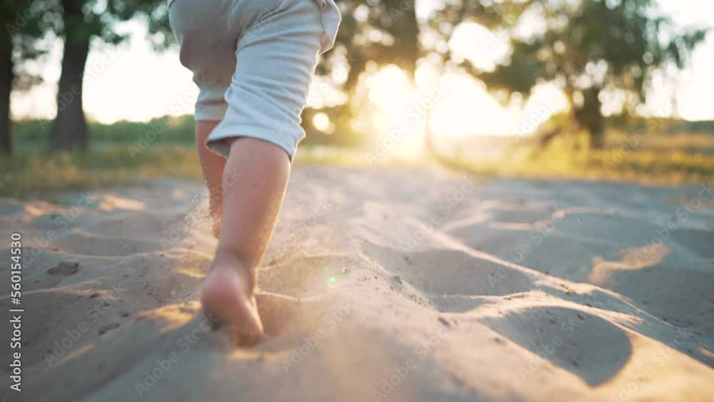 Feet running on the sand on beach. Child runs in the sun. Happy summer ...