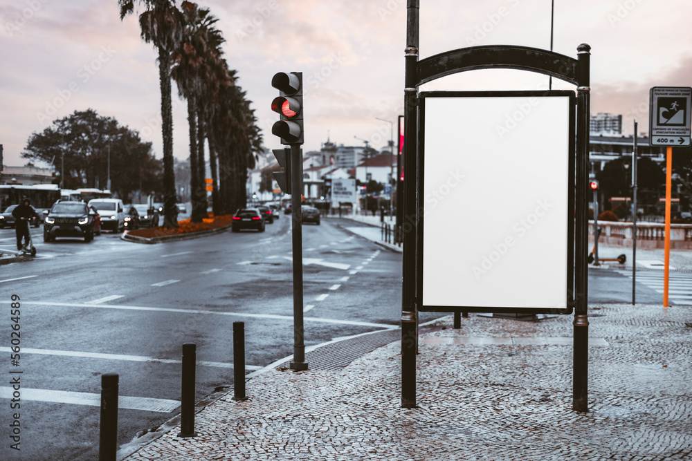 Blank placard mockup next to a traffic light beside a wide road; an ...