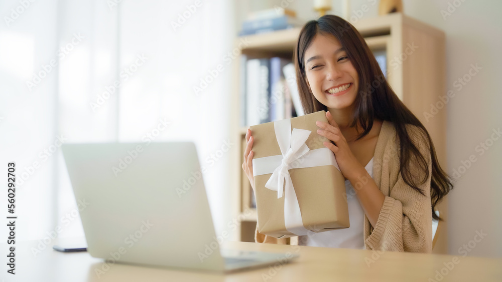 Young asian woman using computer laptop at home. Female showing gift ...