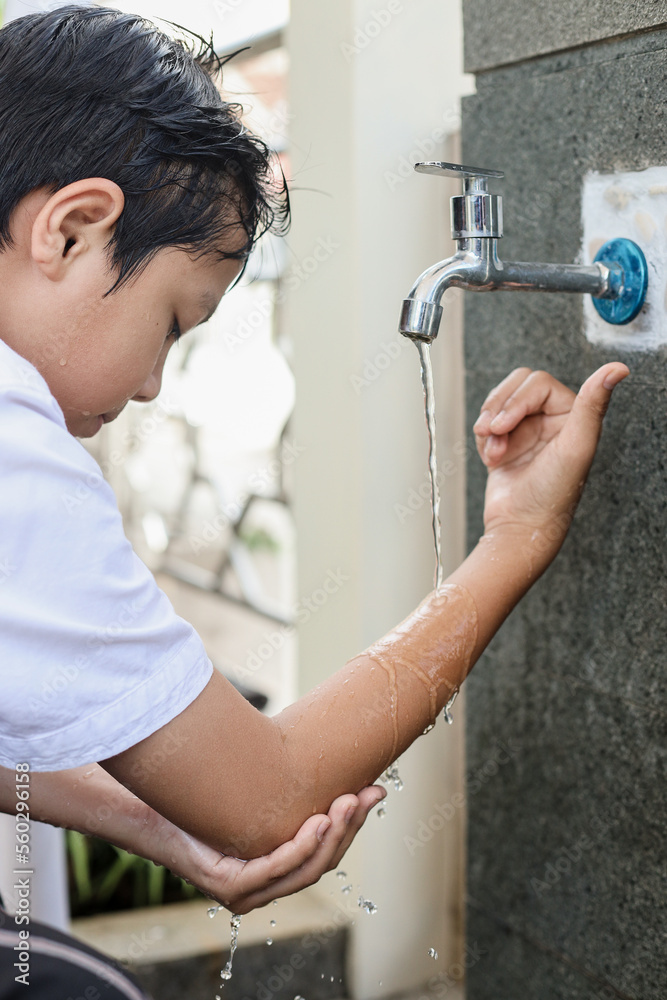 Side view of muslim kids washing right hand to elbow arms, ablution ...
