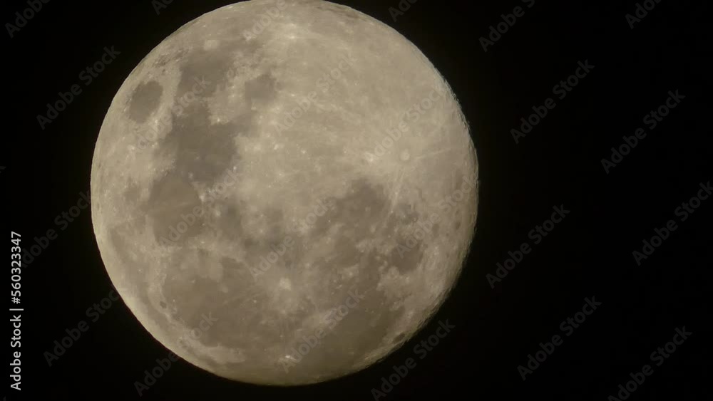 Timelapse of a full moon slowly rising in the night sky. Zoomed in ...