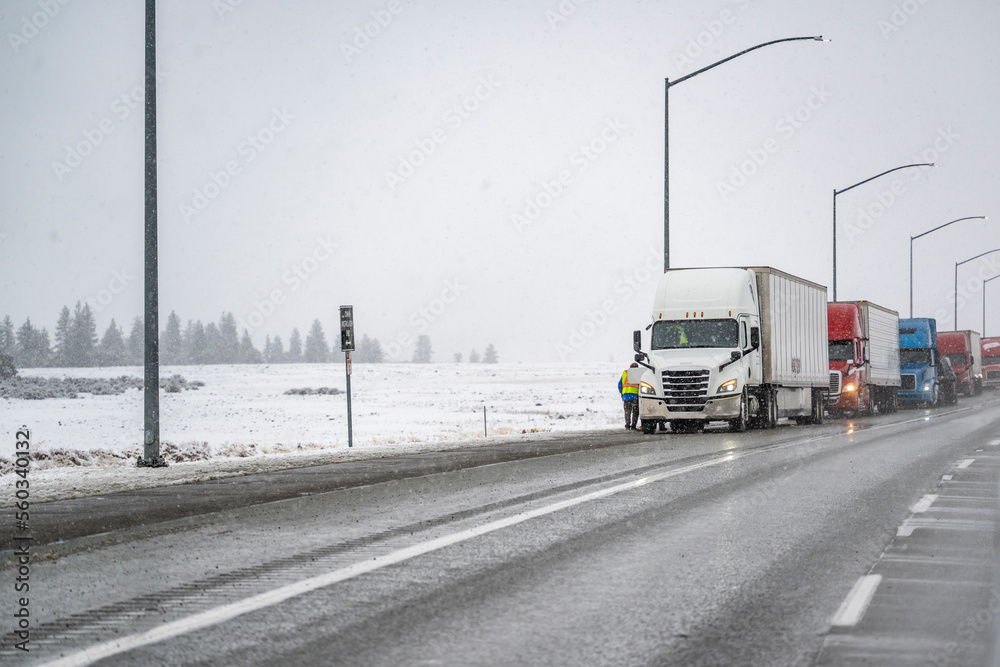 Truck driver is installing chains on semi truck standing on highway ...