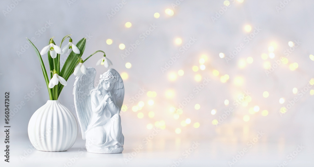 Praying angel figurine and snowdrops flowers on table, abstract ...