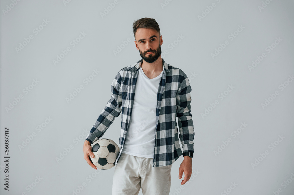 Football fan holding soccer ball. Handsome man is in the studio against ...