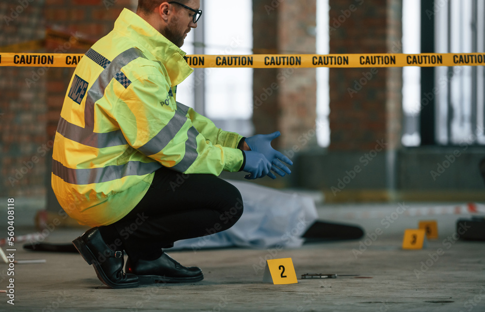 Wearing gloves. Male detective is collecting evidence in a crime scene ...