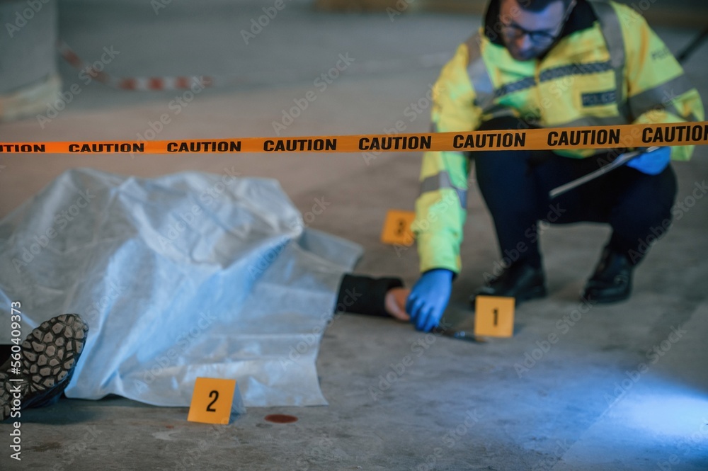 Knife is on the floor. Male detective is collecting evidence in a crime ...