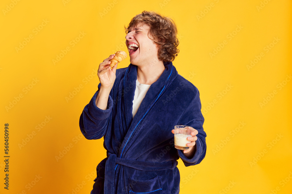 Laughing young man wearing bathrobe and having breakfast isolated over ...
