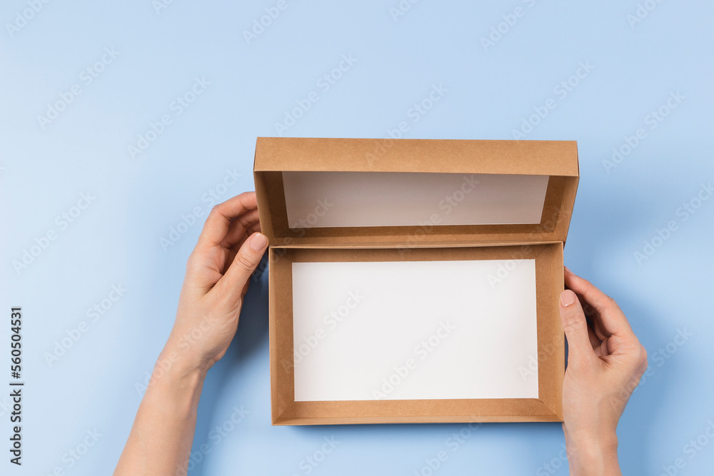 Top view to female hands holding empty brown cardboard box on light ...