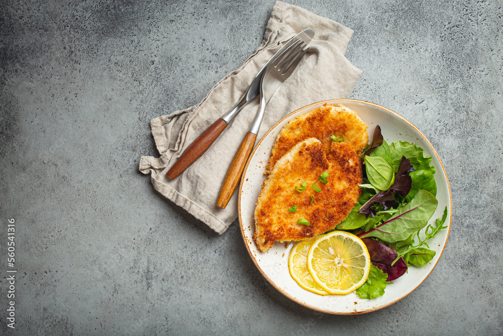 Crispy panko breaded fried chicken fillet with green salad and lemon on ...